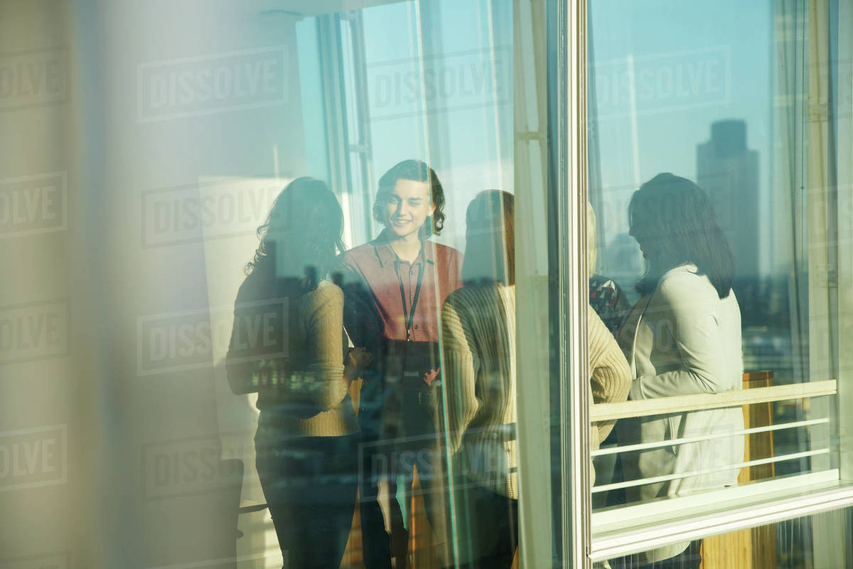 Business people talking in sunny office window - Stock Photo - Dissolve