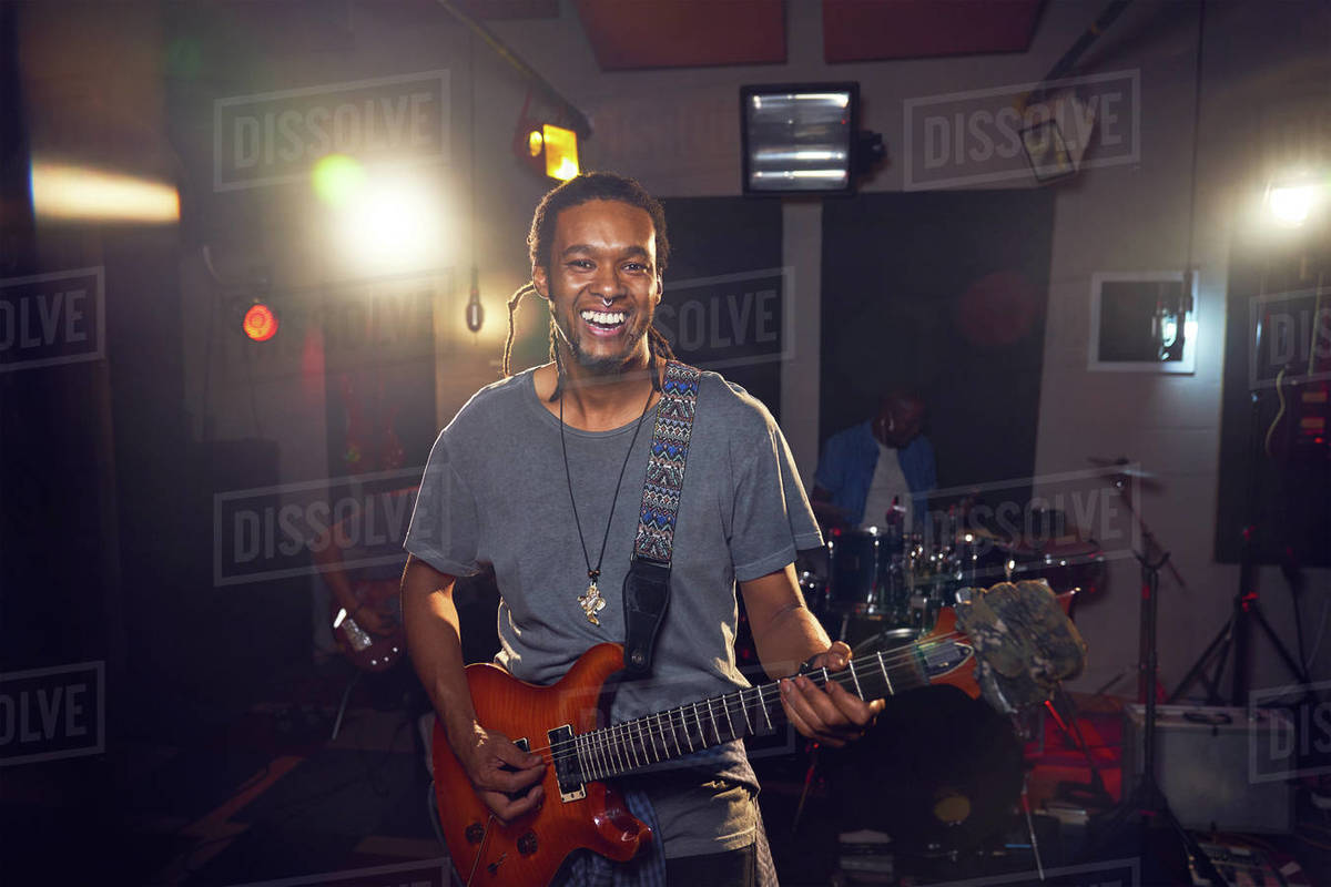 Portrait confident male musician playing guitar in recording studio ...