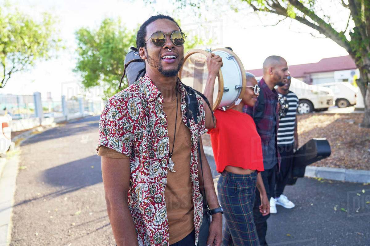 Happy musicians carrying musical instruments on in parking lot - Stock ...