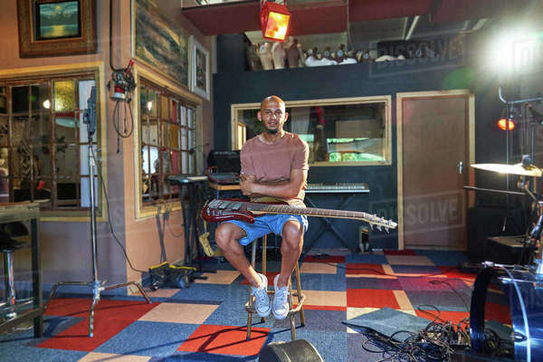 Portrait confident male musician with guitar in recording studio ...