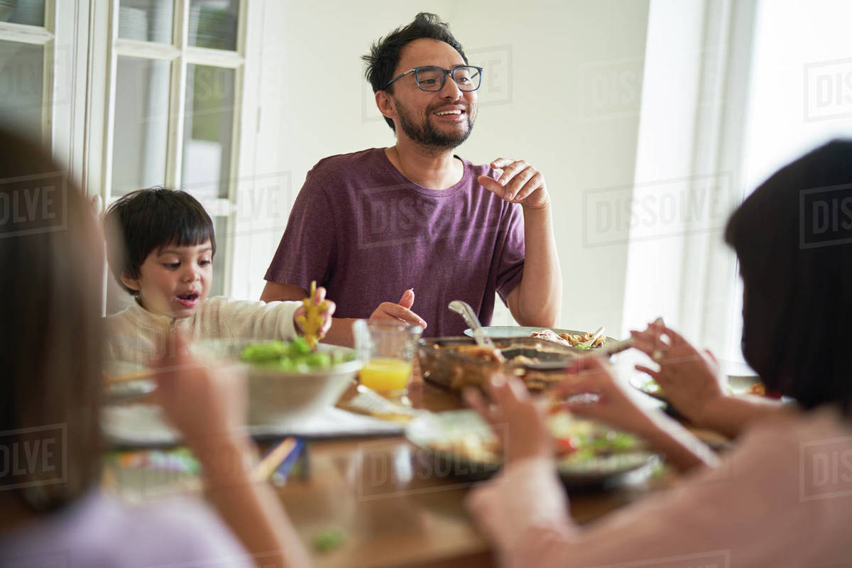 Happy family eating dinner at table - Stock Photo - Dissolve