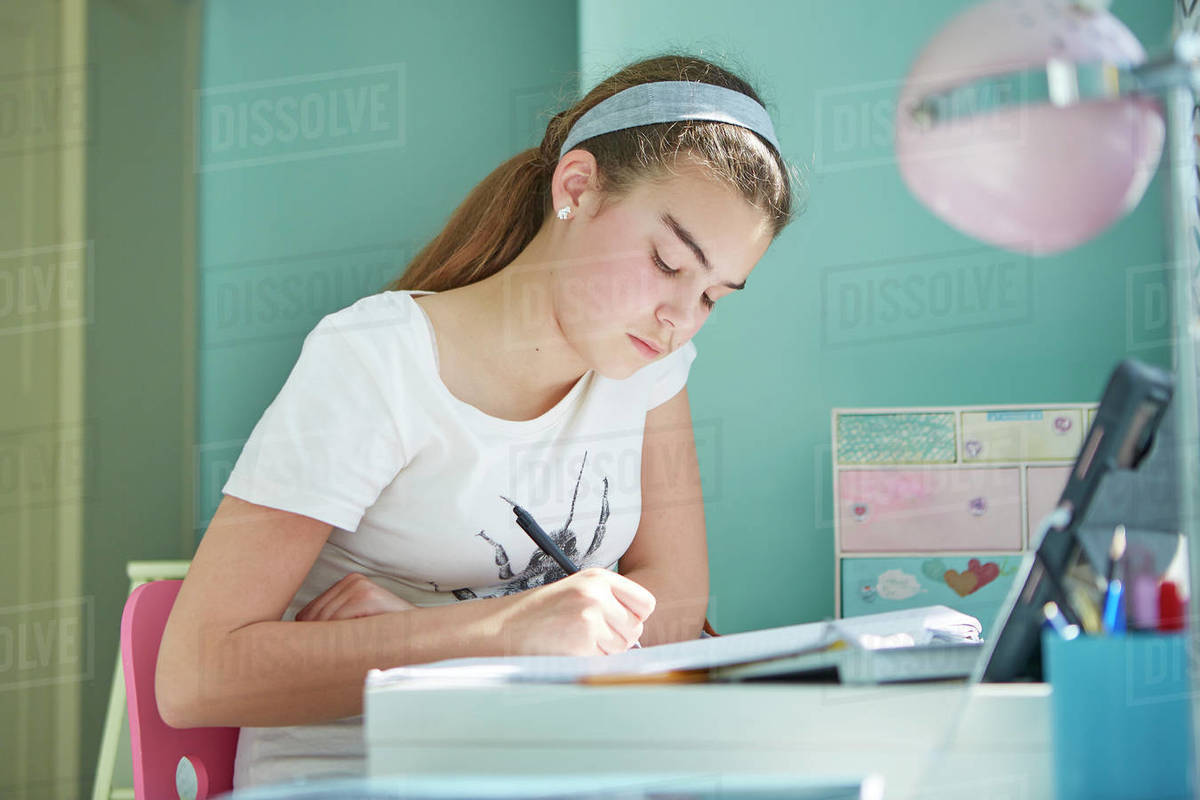 Girl doing homework at desk in bedroom - Stock Photo - Dissolve