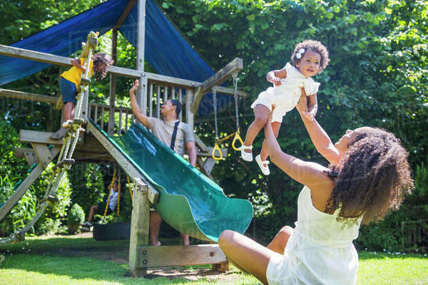 Happy family playing at playground set in sunny summer backyard ...