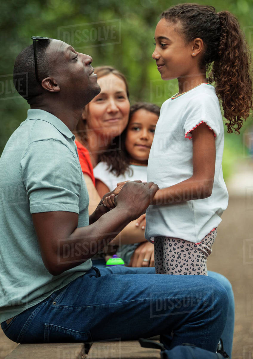 Happy family talking on park bench - Stock Photo - Dissolve