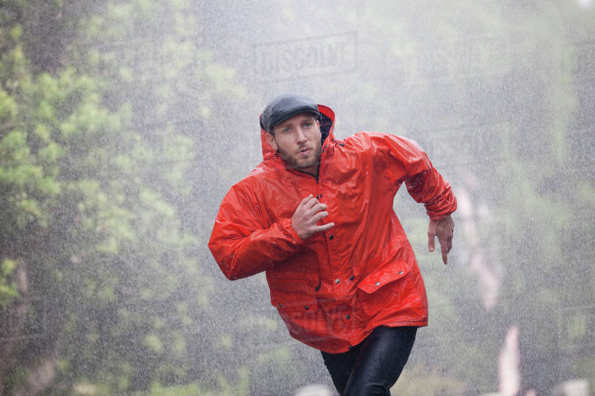 Man in raincoat running in rain - Royalty-free Stock Photo | Dissolve