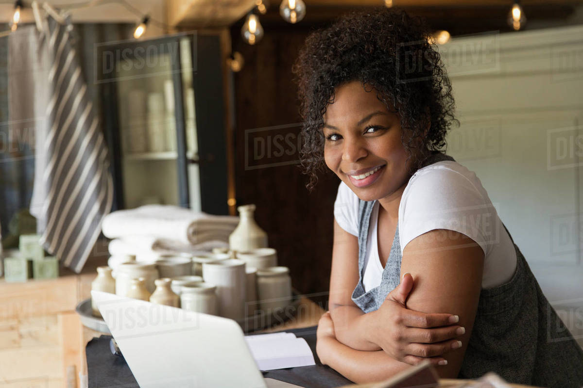 Portrait confident female shop owner working at laptop on counter ...