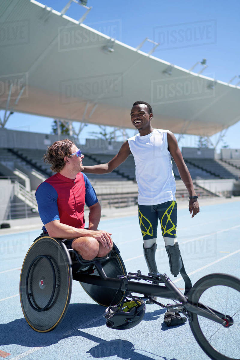Happy male amputee and paraplegic athlete on sunny sports track ...
