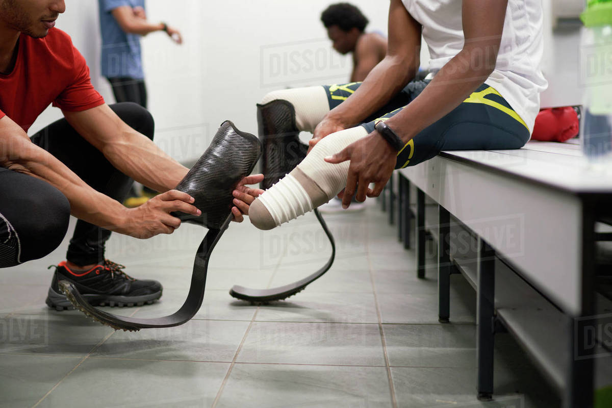 Coach helping male amputee athlete with running blade prosthetic ...