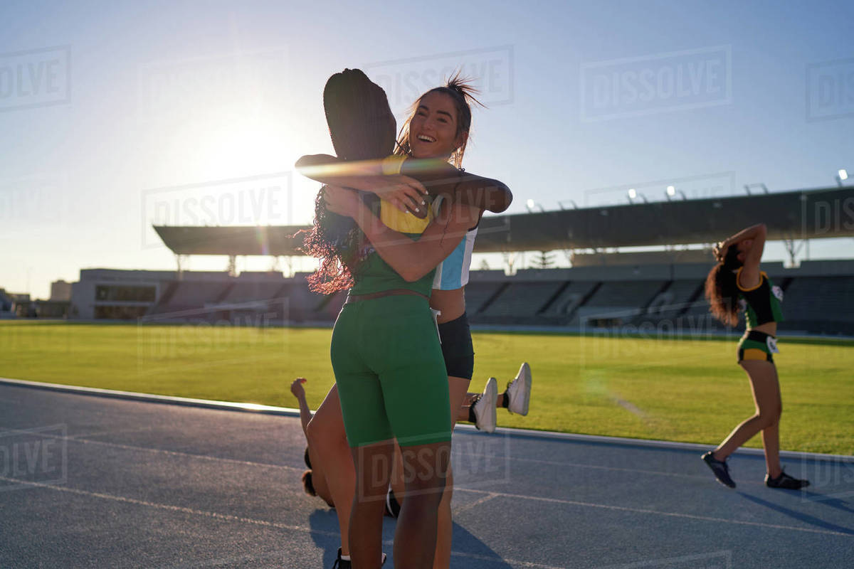 Happy female track and field athletes hugging on sunny track - Royalty ...