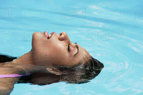 Woman floating in pool - Stock Photo - Dissolve