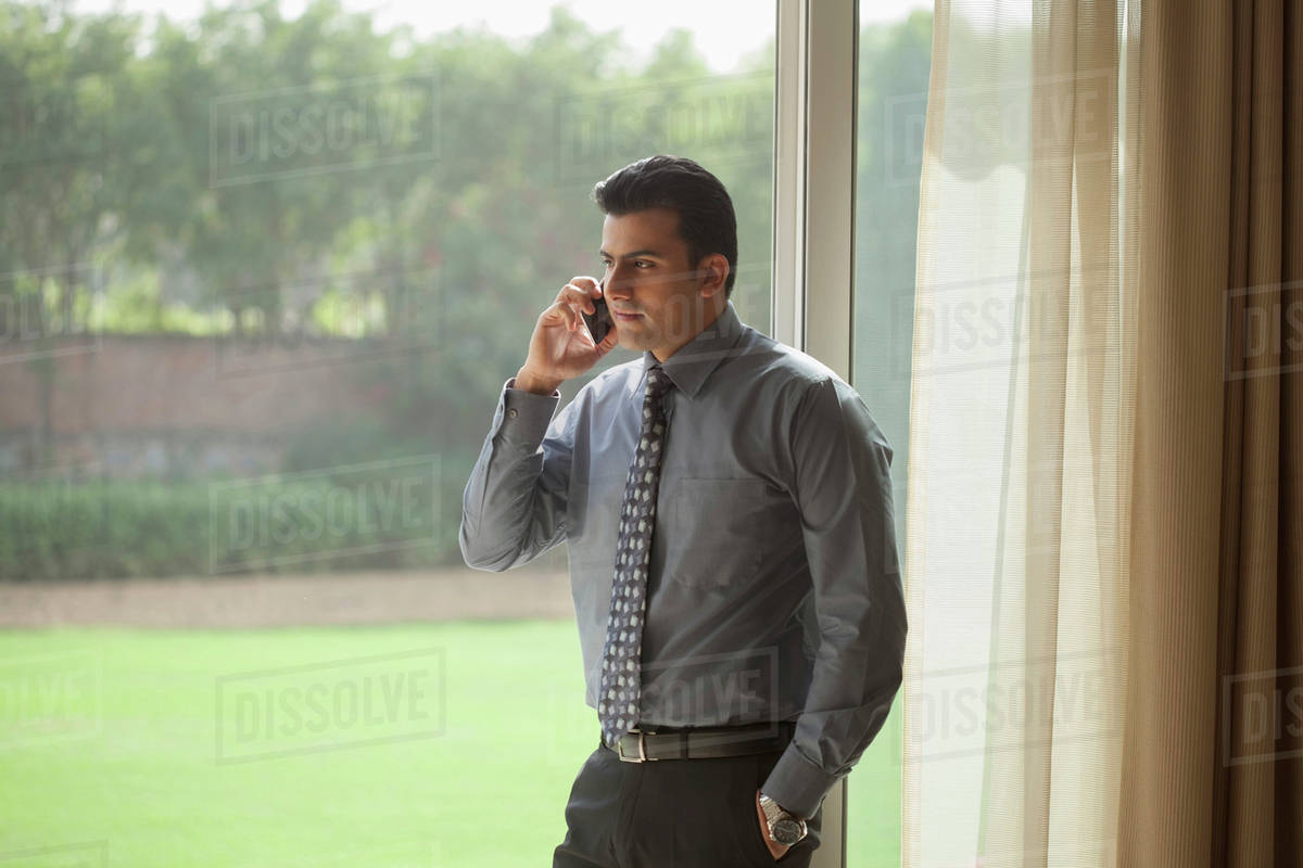 Businessman talking on mobile phone in house - Royalty-free Stock Photo ...