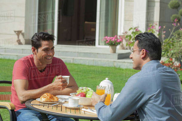 Two men eating breakfast in garden - Royalty-free Stock Photo | Dissolve