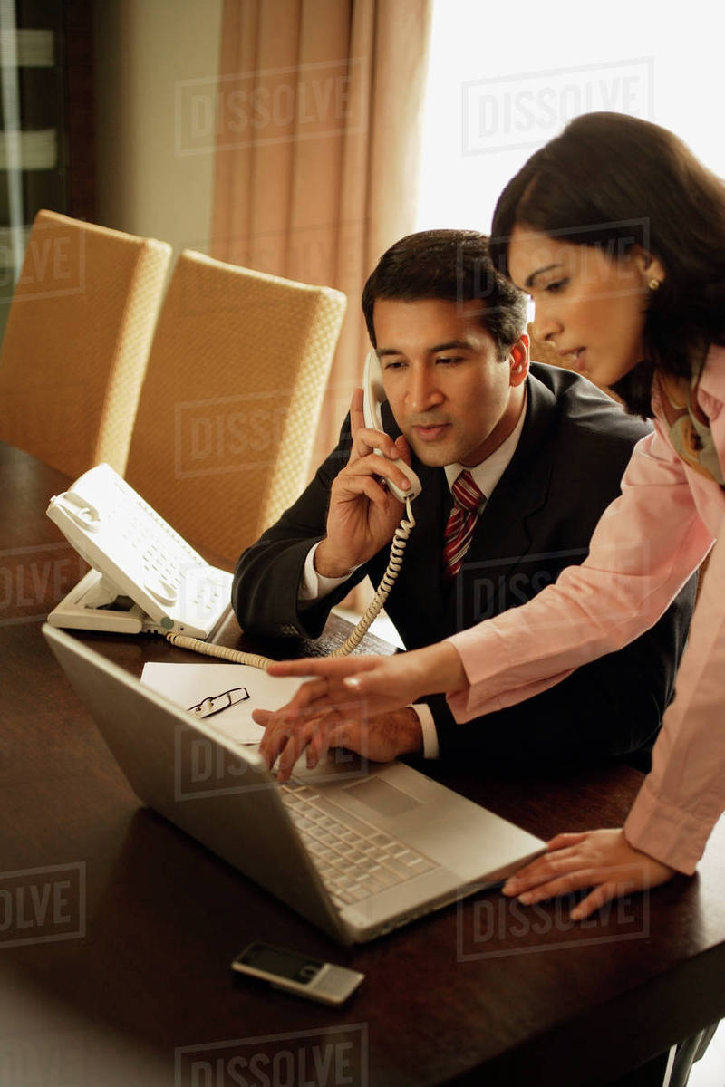 Business associates meeting, one on phone - Stock Photo - Dissolve