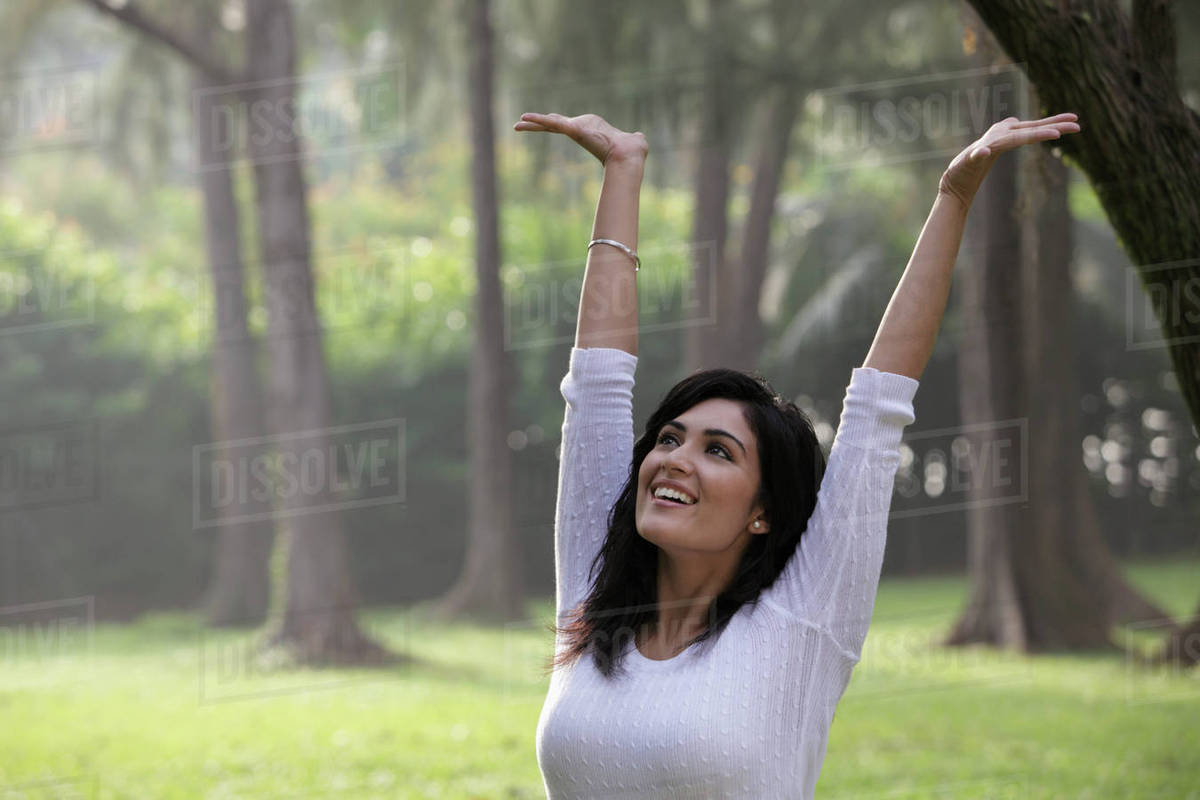 Head shot of young woman smiling with arms raised over head - Royalty ...