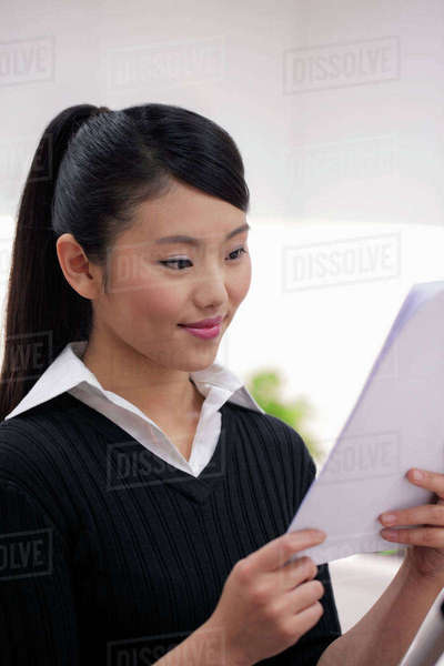 Head shot of young woman looking at paper - Stock Photo - Dissolve