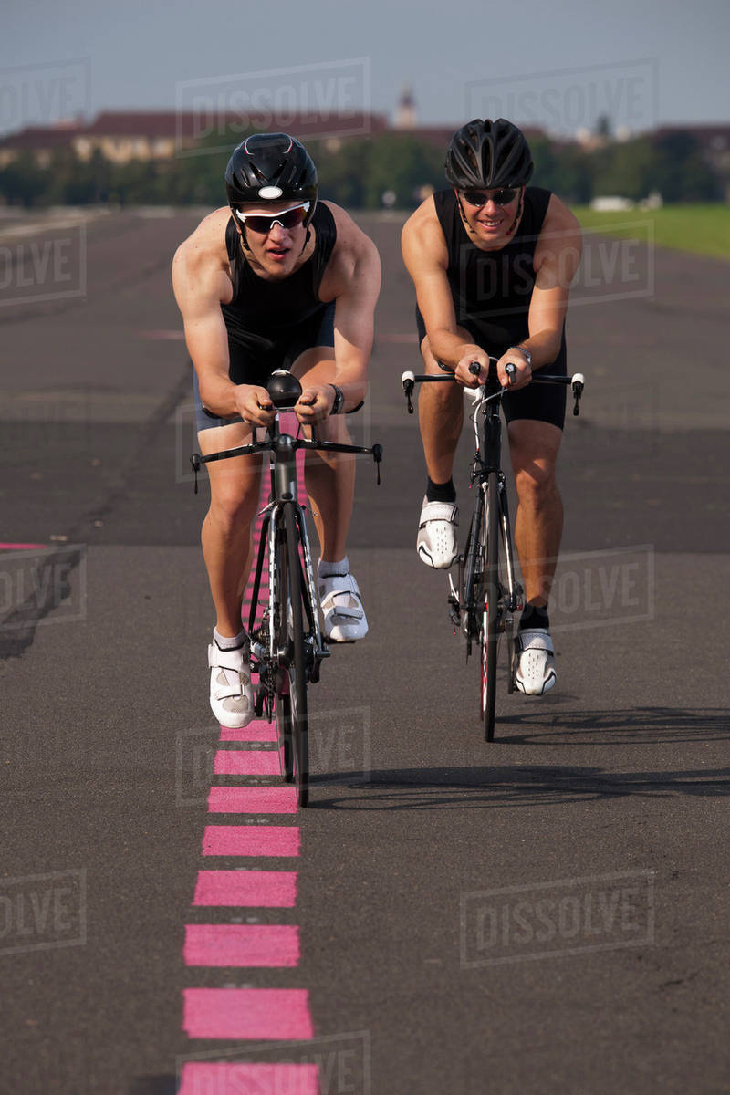 Two cyclists on racing bicycles cycling on a marked road - Royalty-free ...