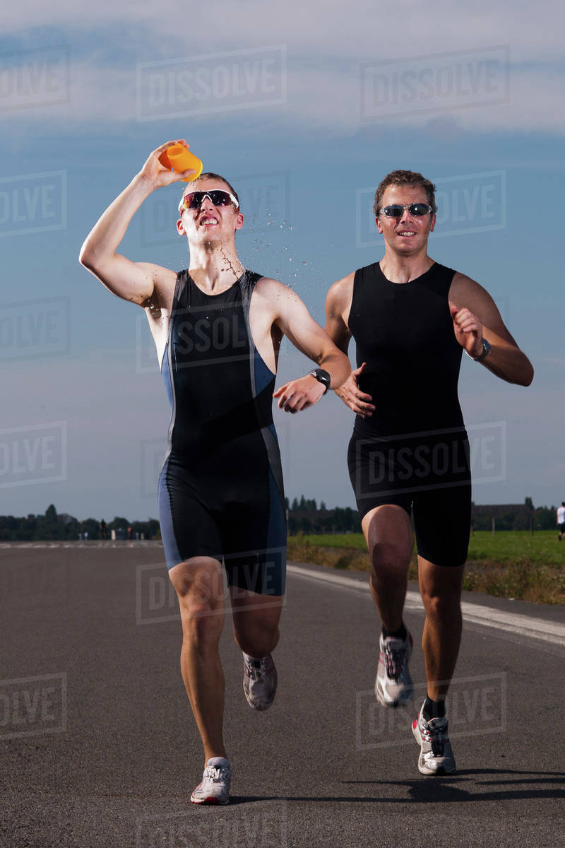 A runner pouring water on his face while running in a race - Royalty ...