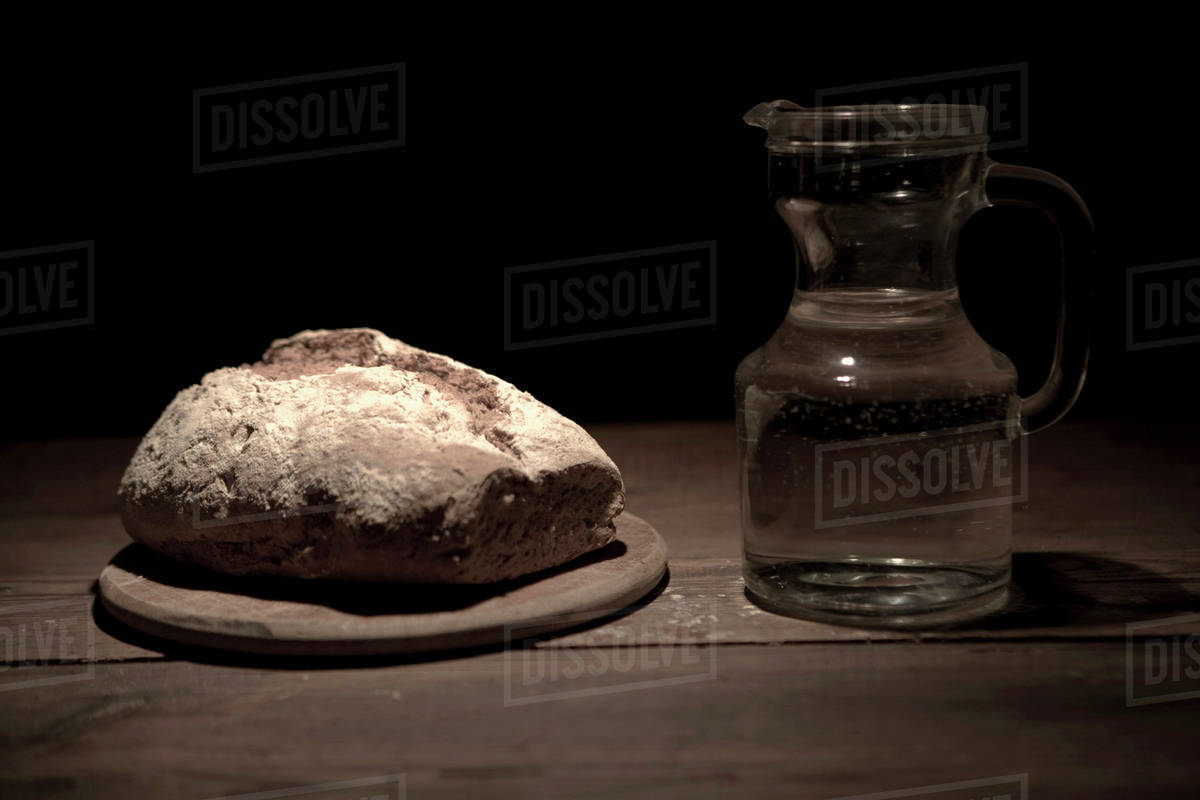 A loaf of bread and a jug of water on a table - Stock Photo - Dissolve