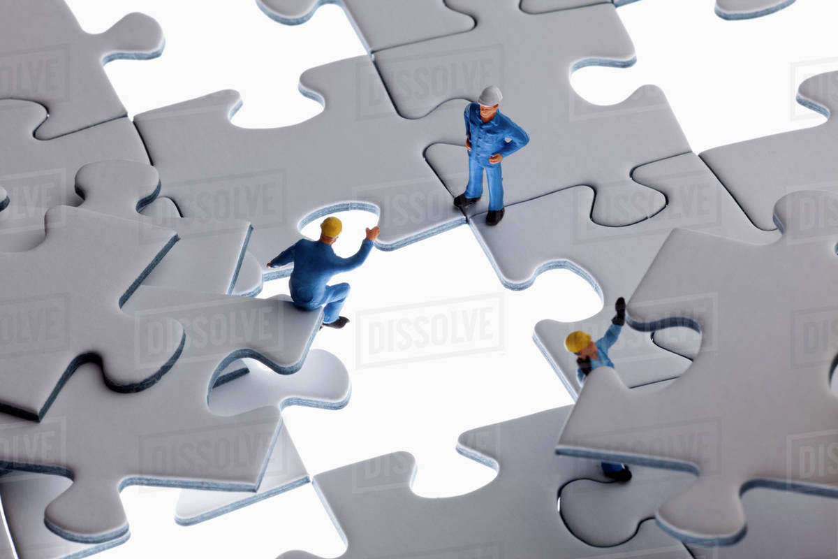 Miniature workmen working on assembling a jigsaw puzzle - Royalty-free ...
