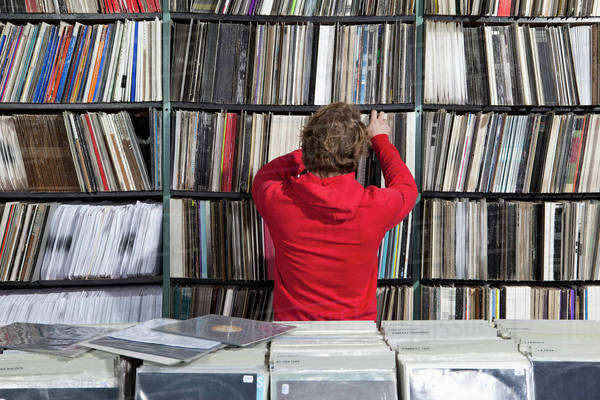 A young man selecting a record from a shelf in a record store - Royalty ...