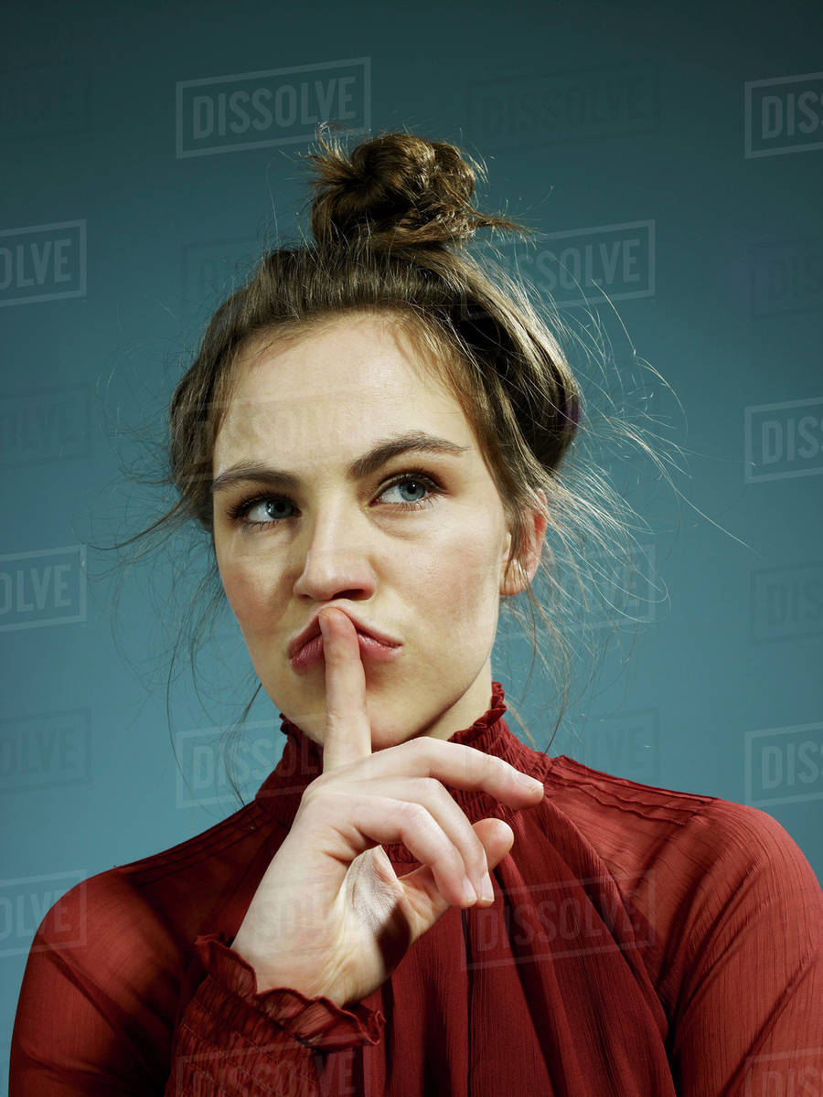 A young hip woman with her index finger on her lips, thinking - Royalty ...