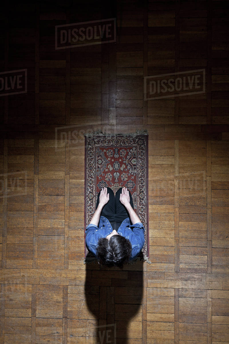 A man praying on a mat - Stock Photo - Dissolve