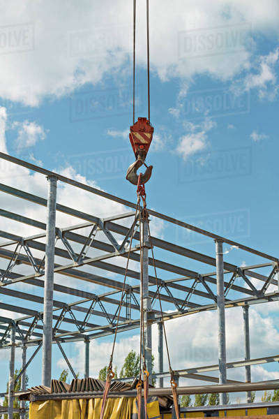 Crane hook with construction site in background - Stock Photo - Dissolve