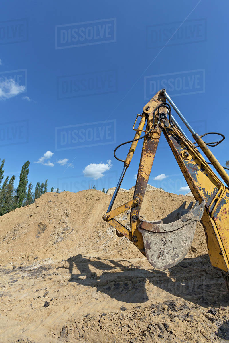 Digger beside sand mounds - Stock Photo - Dissolve
