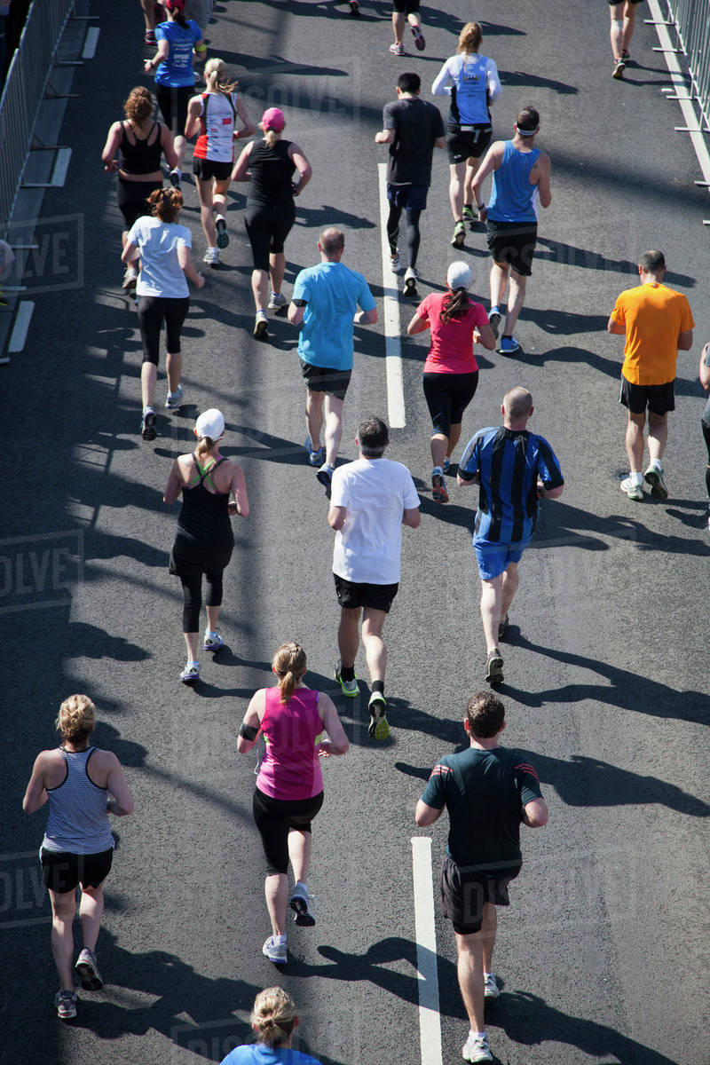 Rear view of people running in a marathon - Stock Photo - Dissolve