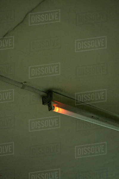 A broken fluorescent light emitting a faint orange light - Stock Photo ...