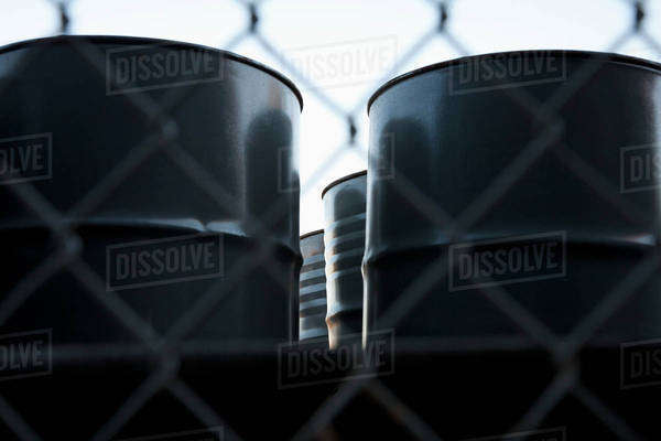 Black barrels behind wire mesh fence - Royalty-free Stock Photo | Dissolve