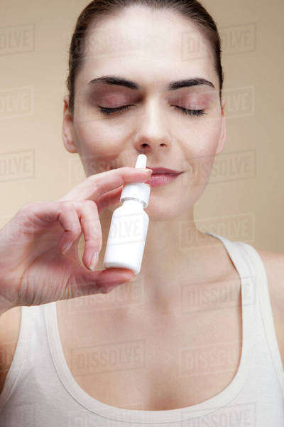 A serenely smiling young woman inhaling nasal spray - Stock Photo ...