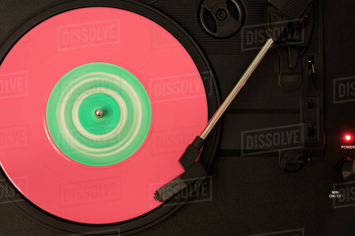 A pink and green vinyl record playing on a turntable - Royalty-free ...