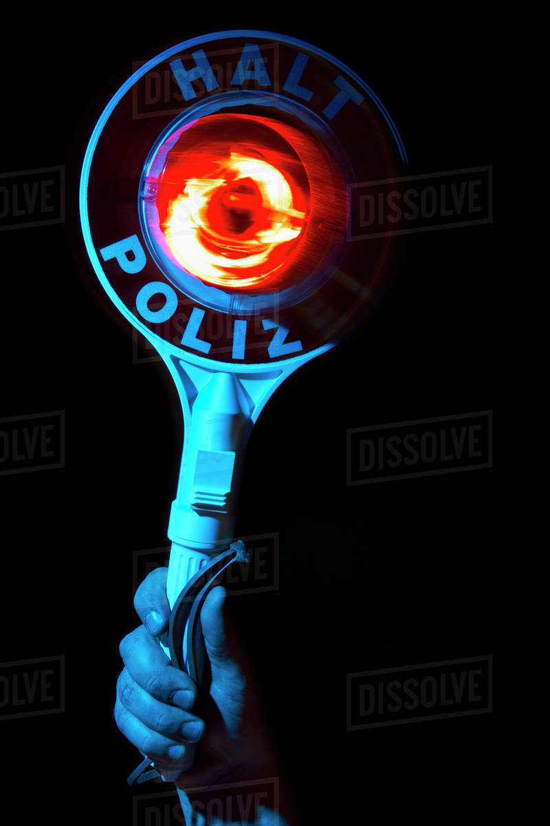 A hand holding a police warning sign with the German Halt Polizei on it ...