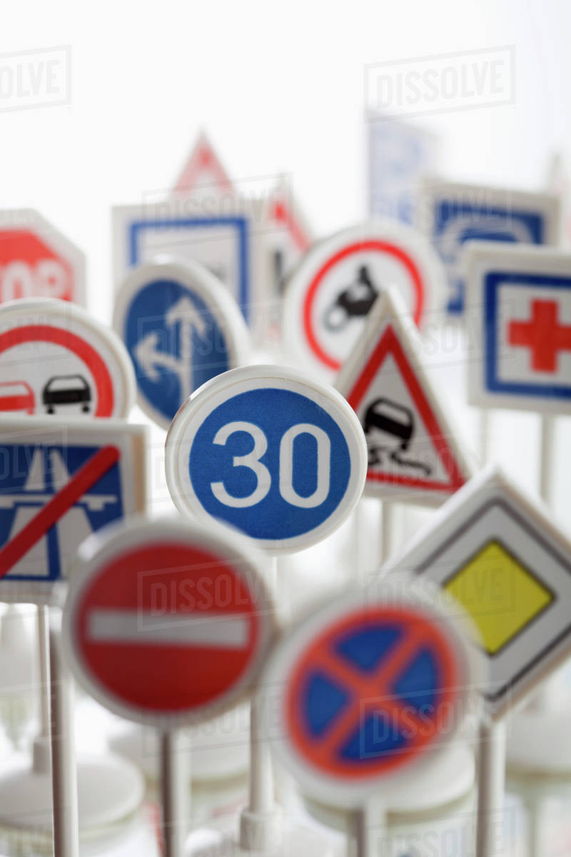 A toy speed limit sign surrounded by other various road warning signs ...