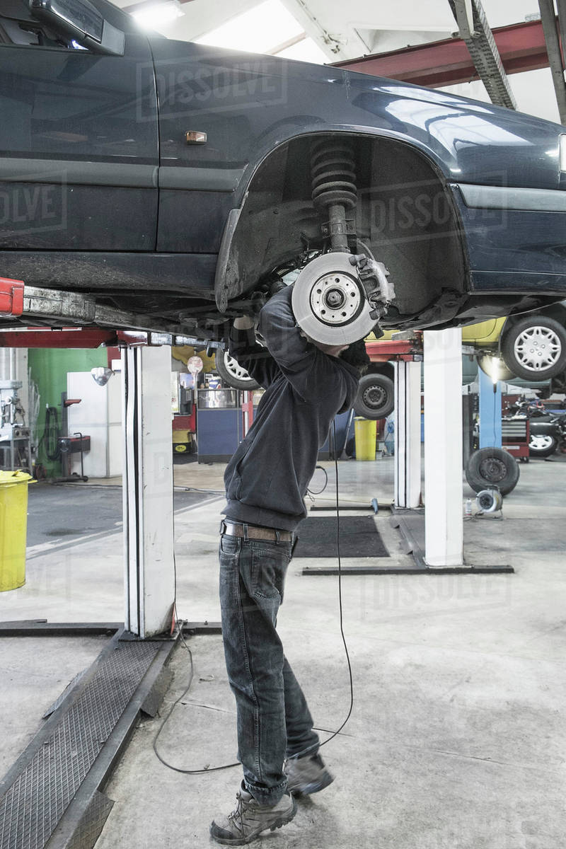 Side view of male mechanic repairing car in auto repair shop - Royalty ...