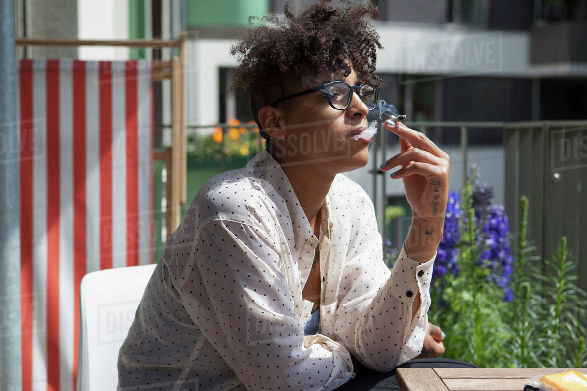 Young woman smoking at porch - Royalty-free Stock Photo | Dissolve