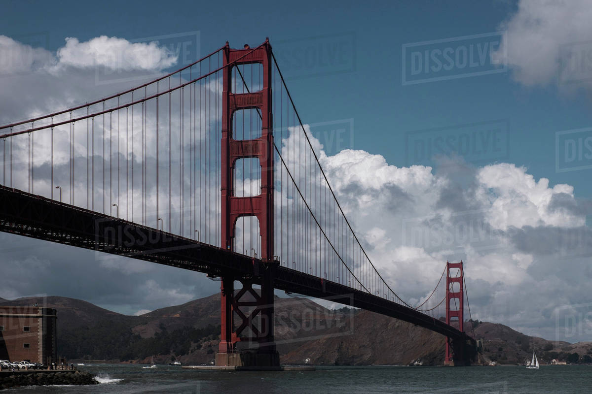 Low angle view of Golden Gate Bridge over river against cloudy sky ...