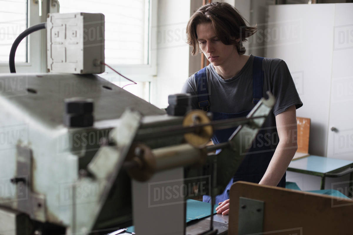 Young manual worker operating machine in factory - Stock Photo - Dissolve