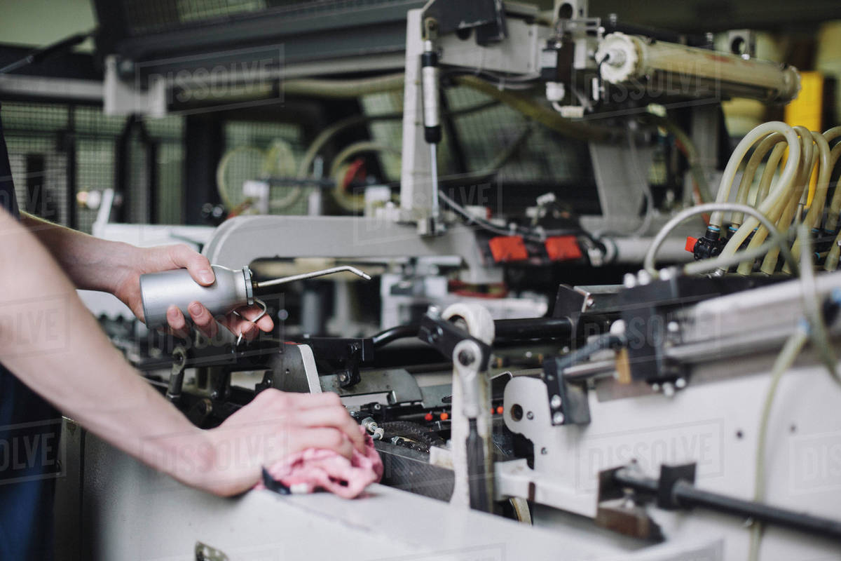 Cropped image of manual worker oiling machine in factory - Stock Photo ...