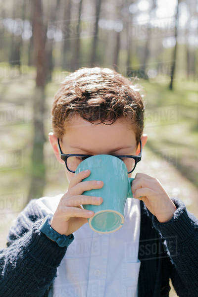 Close-up of boy drinking coffee in forest - Stock Photo - Dissolve