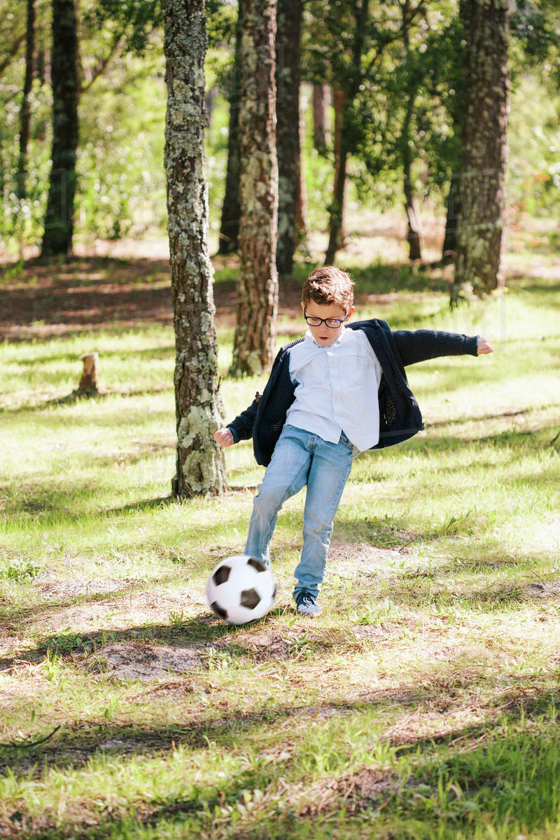 Full length of boy playing soccer in forest - Royalty-free Stock Photo ...