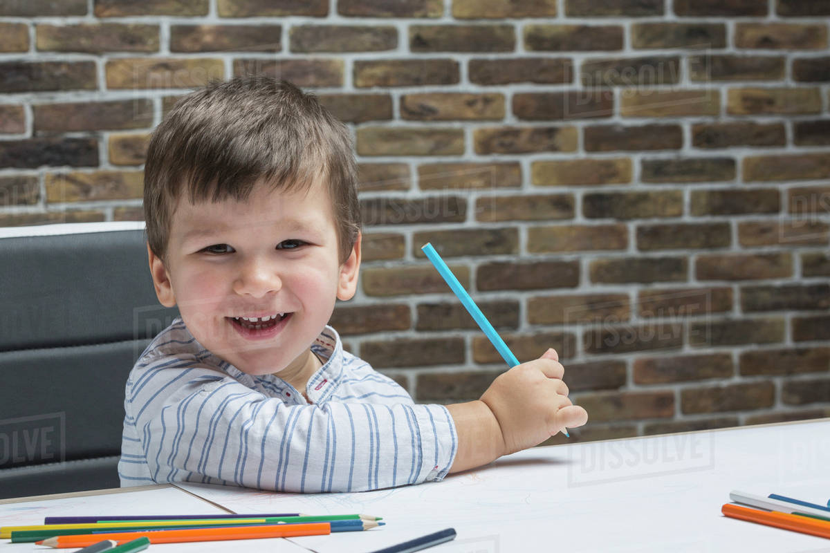 Portrait of happy boy drawing at table in house - Stock Photo - Dissolve