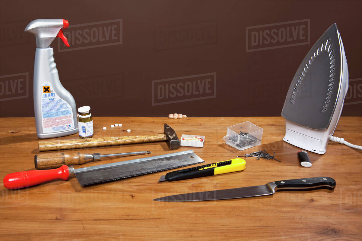 A child's fingers grasping a table full of dangerous objects, studio ...