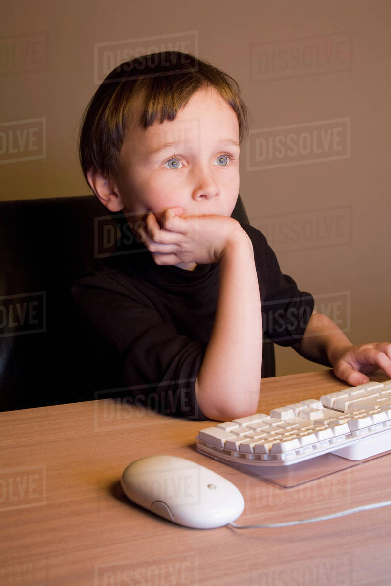 A boy using a computer mouse and keyboard - Stock Photo - Dissolve