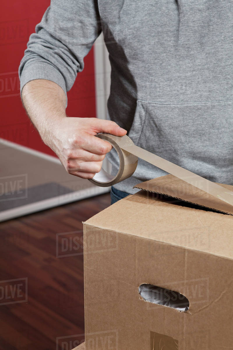 A man taping a moving box shut, midsection - Royalty-free Stock Photo ...