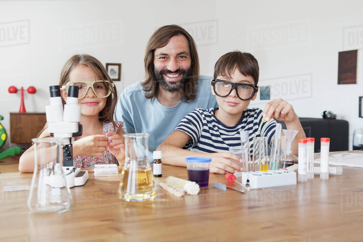 Portrait of father and children doing science experiment at home ...