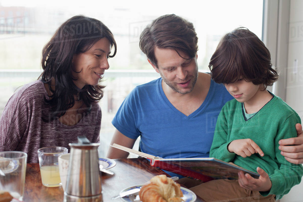 Family at dining table reading book - Royalty-free Stock Photo | Dissolve