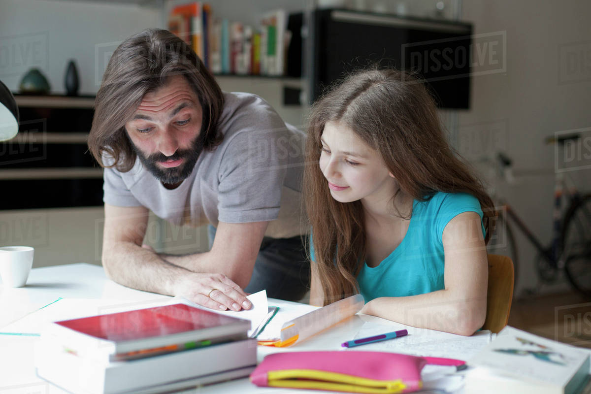 Father assisting daughter in doing homework at table - Royalty-free Stock Photo | Dissolve