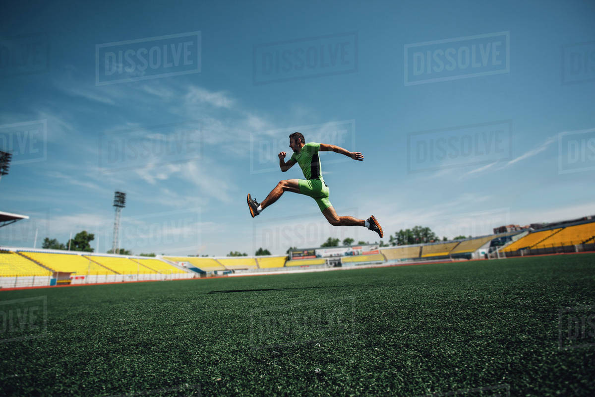 Full length of sporty young man running in stadium during training ...